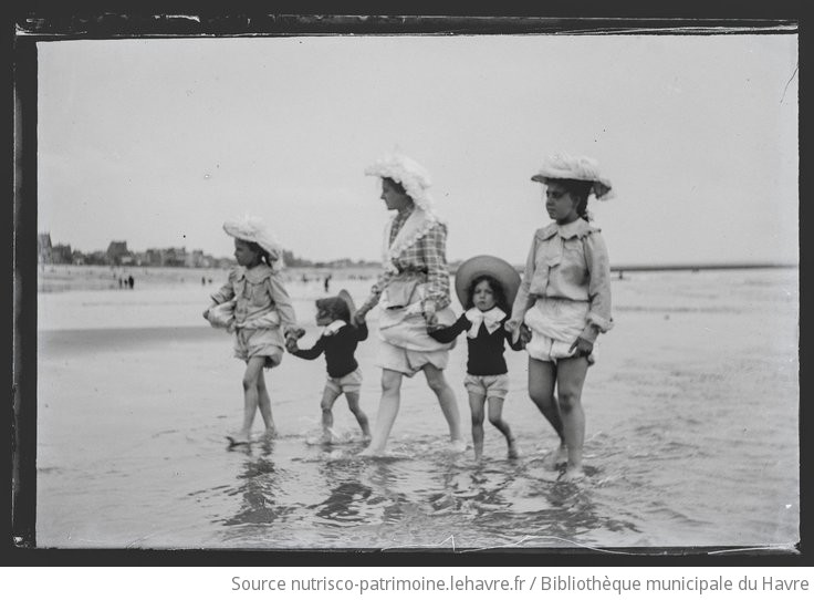 [Deux femmes et trois enfants se promenant à marée basse sur la plage ...